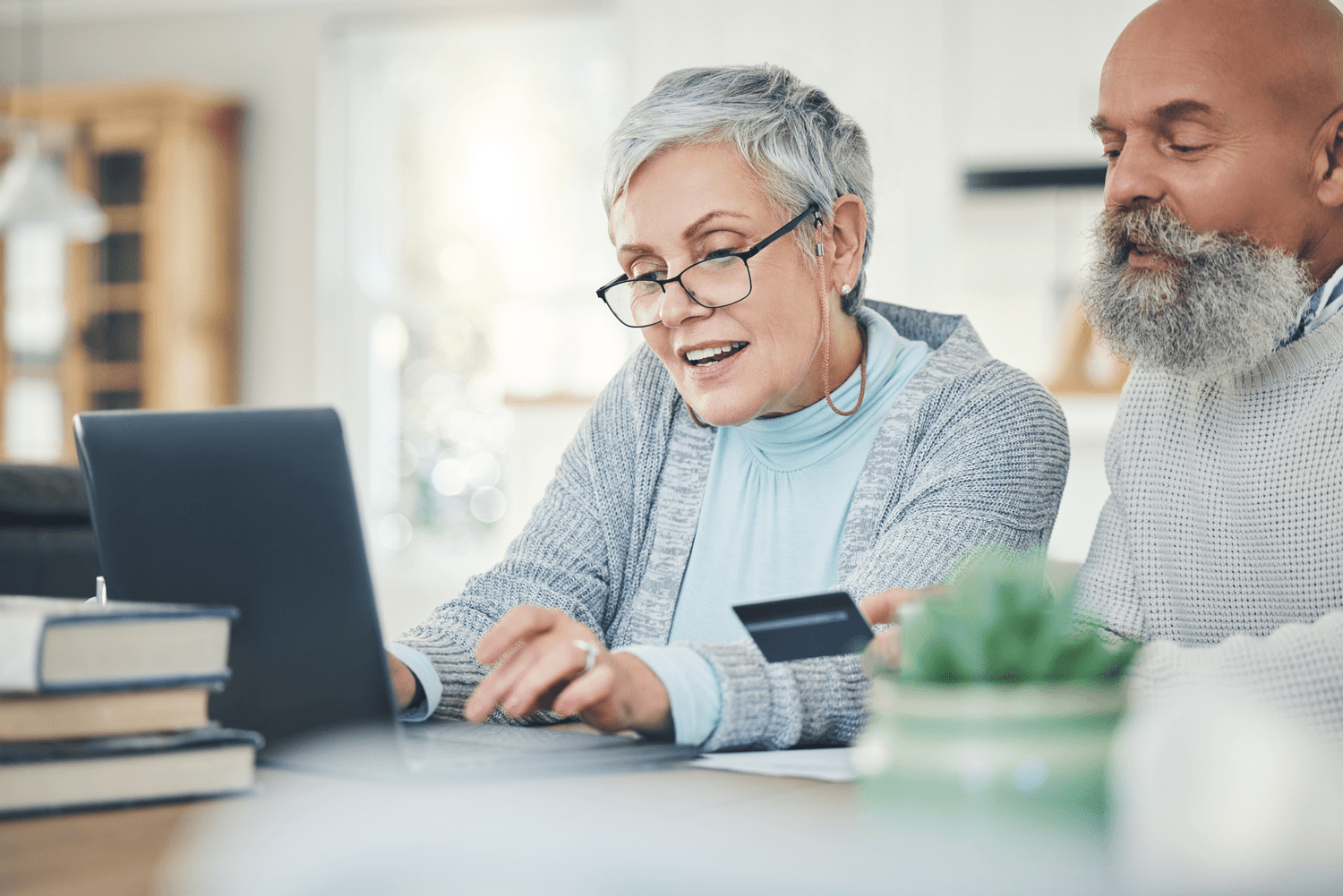 Ein älteres Paar vor dem Laptop, das online shopping betreibt.