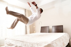 Hüpfender Mann auf einem Bett