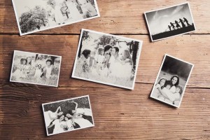 schwarze und weiße Familienfotos liegen auf einem Holztisch